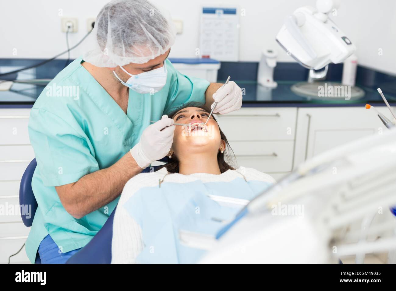 Dentist man examining a latin female patient teeth Stock Photo - Alamy