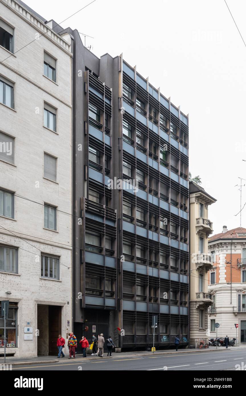 A vertical shot of people walking on a sidewalk and a modern building ...