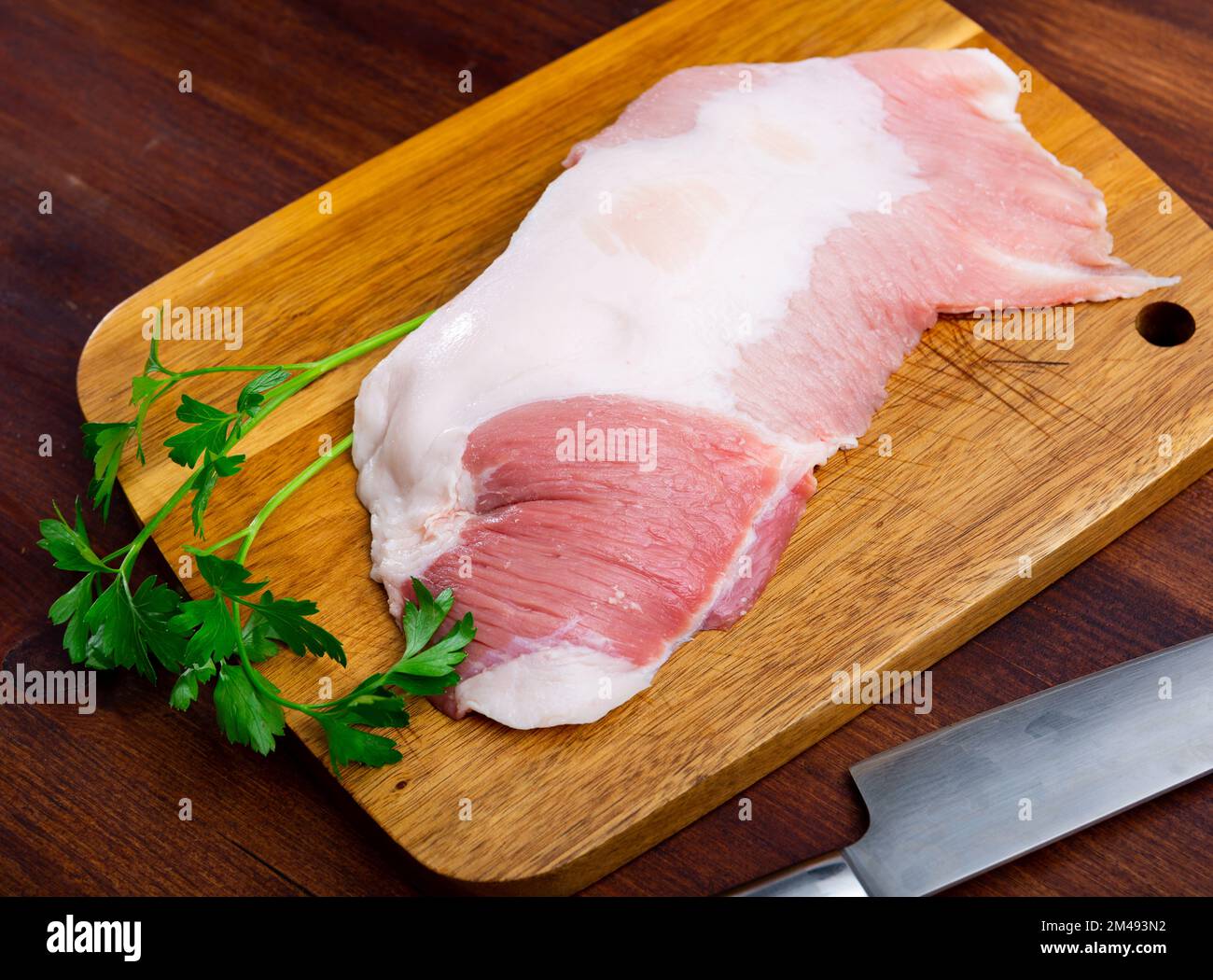 Raw slice of Iberian pork secret on wooden cutting board with ...
