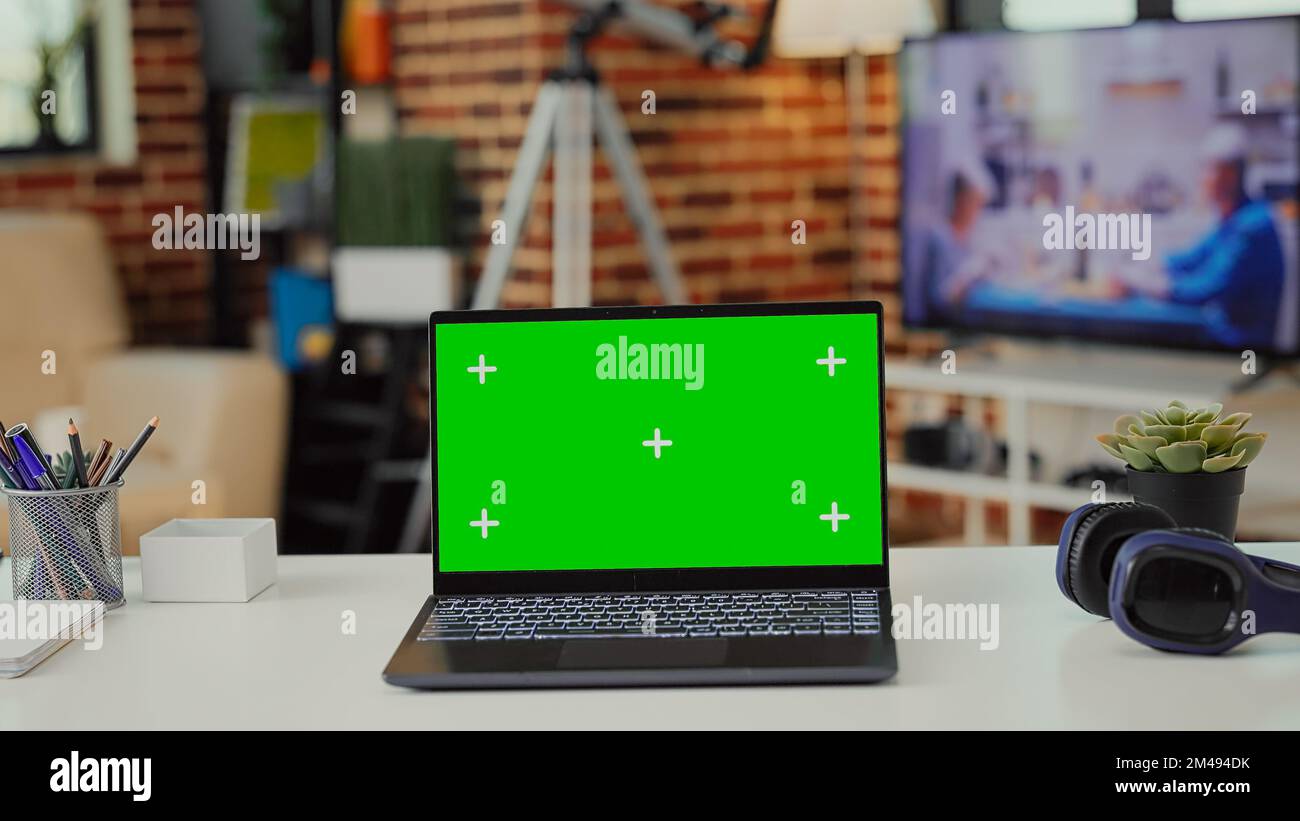 Laptop computer showing green screen isolated display on empty desk at ...