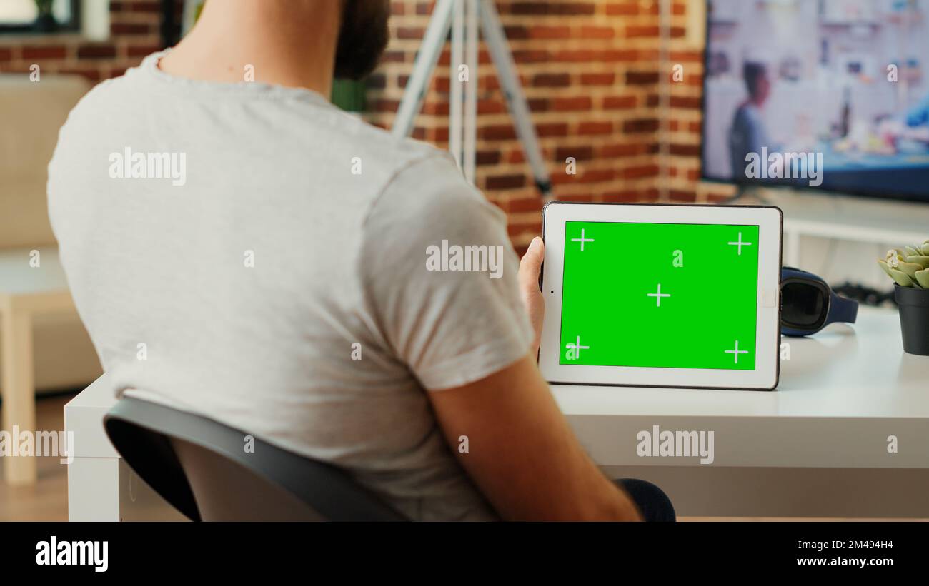 Young man holding modern device with horizontal greenscreen template in ...