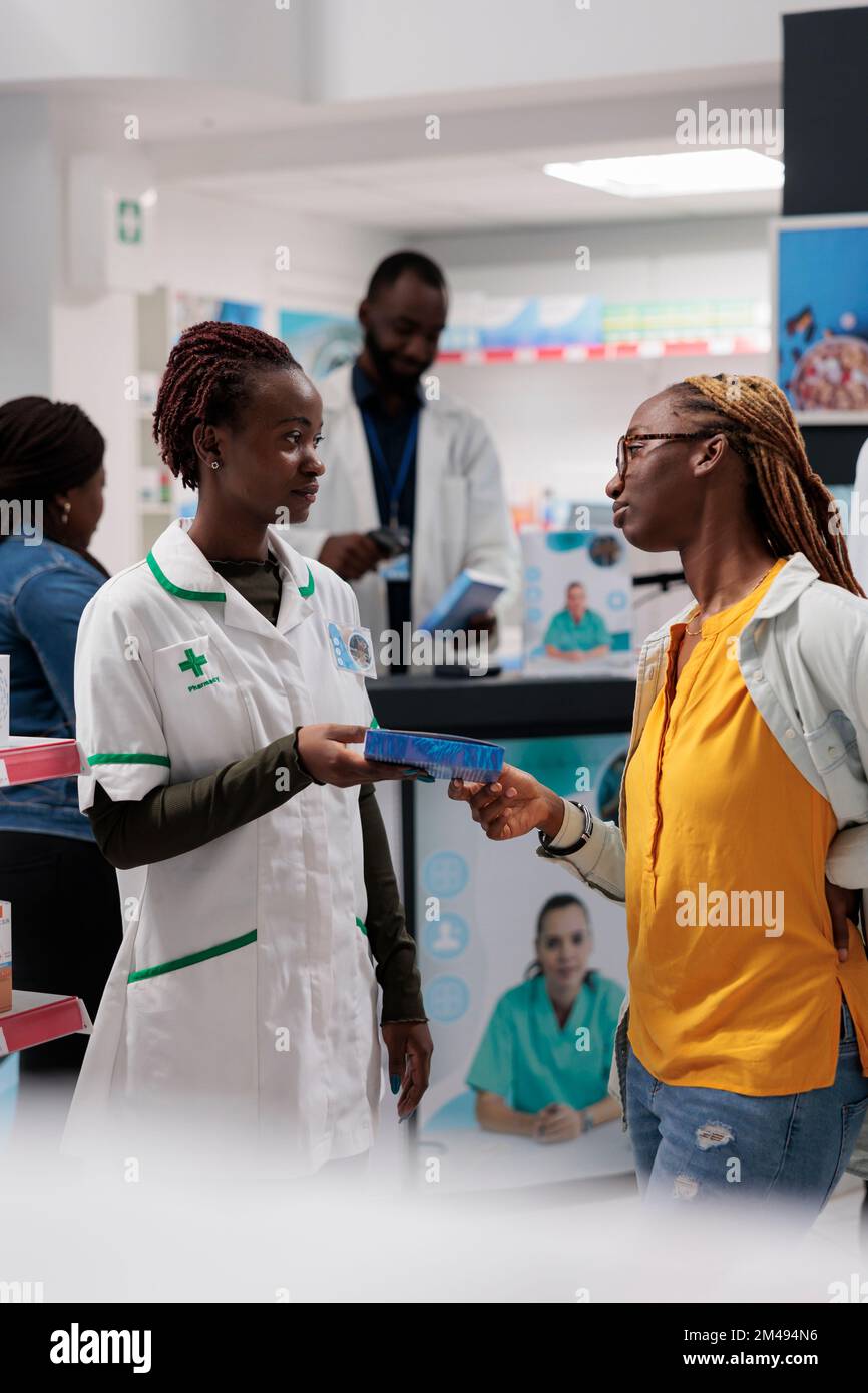 African american pharmacist giving customer backache medication in ...