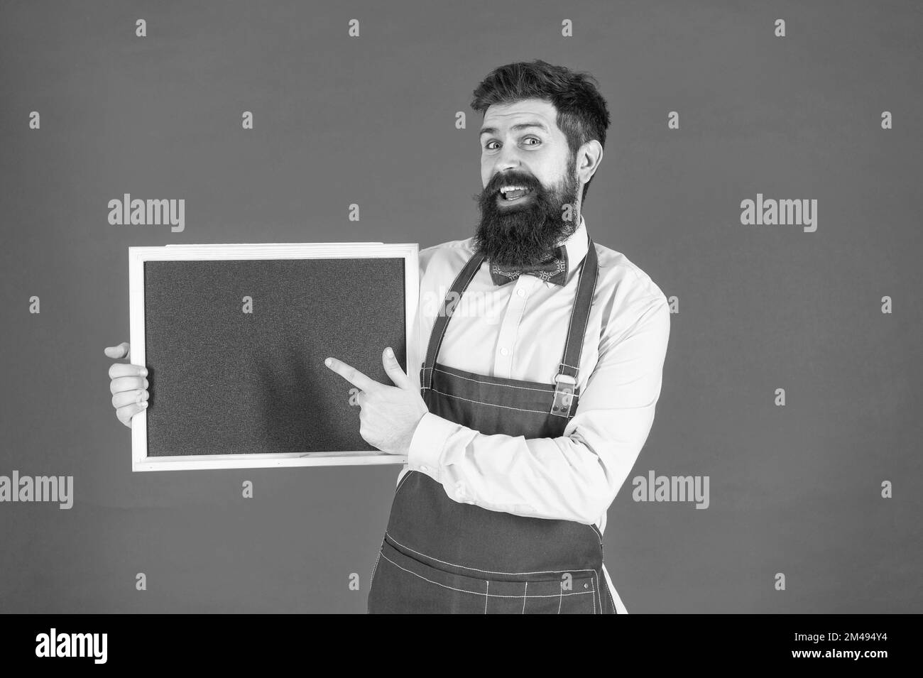 Happy guy in barber apron smile pointing finger at blackboard red ...