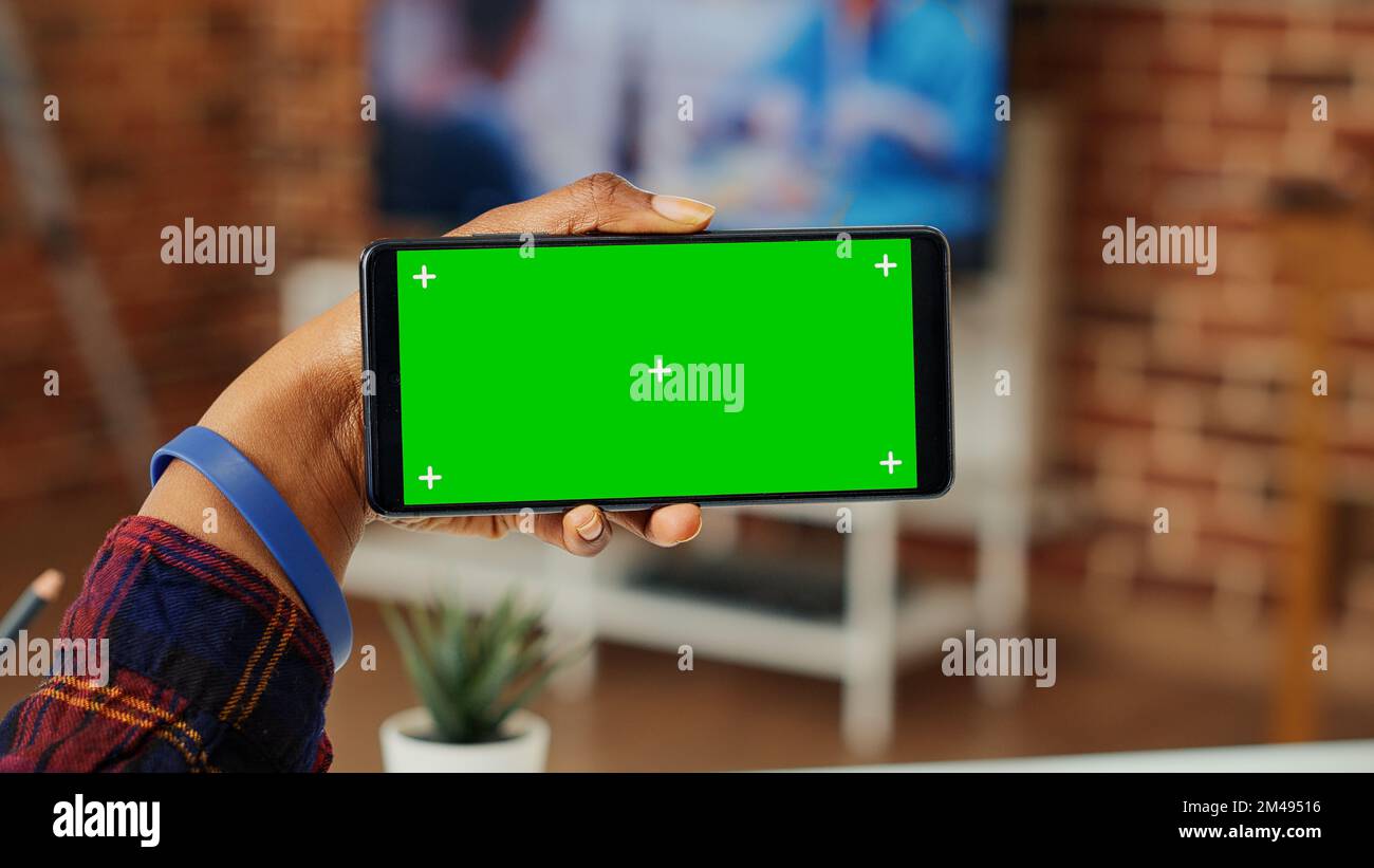 Young adult holding telephone with horizontal greenscreen, analyzing ...