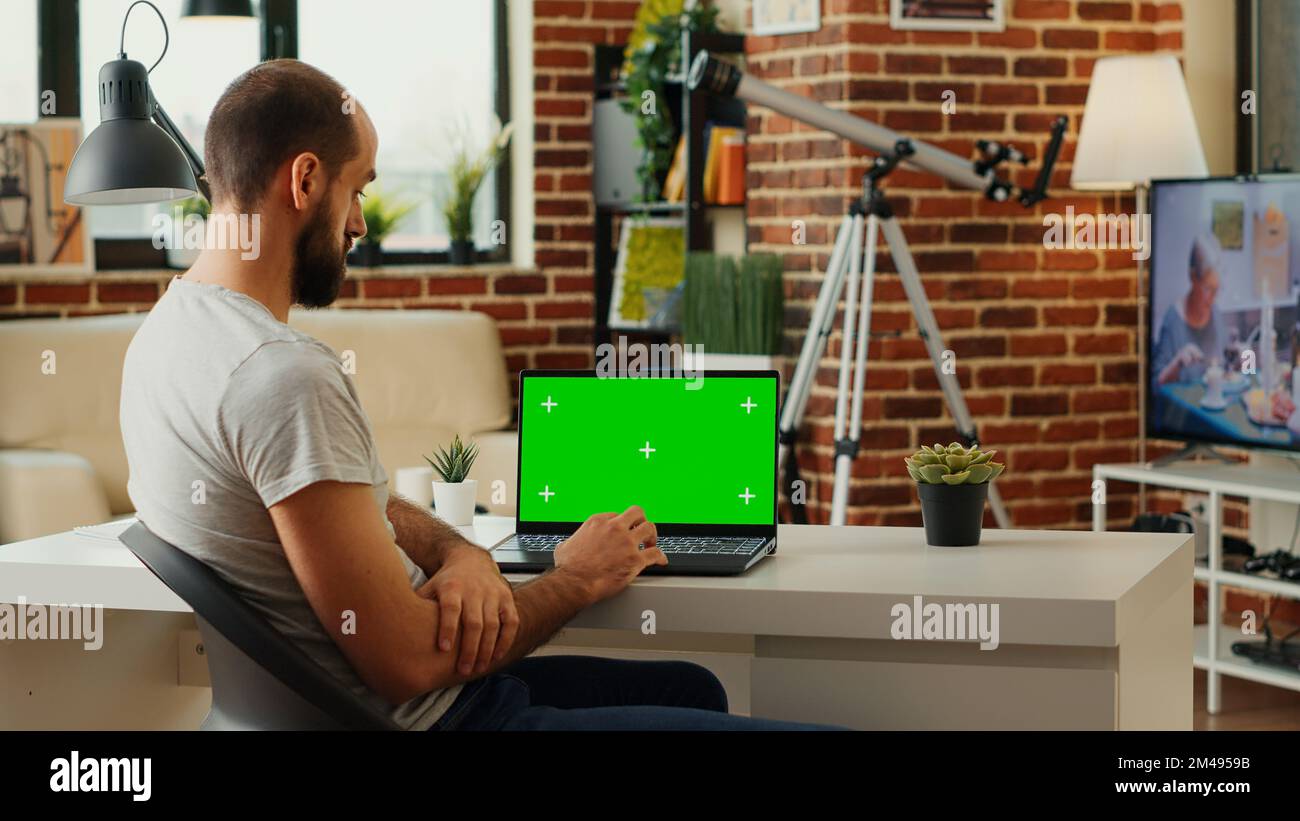 Office employee looking at laptop with greenscreen display and ...