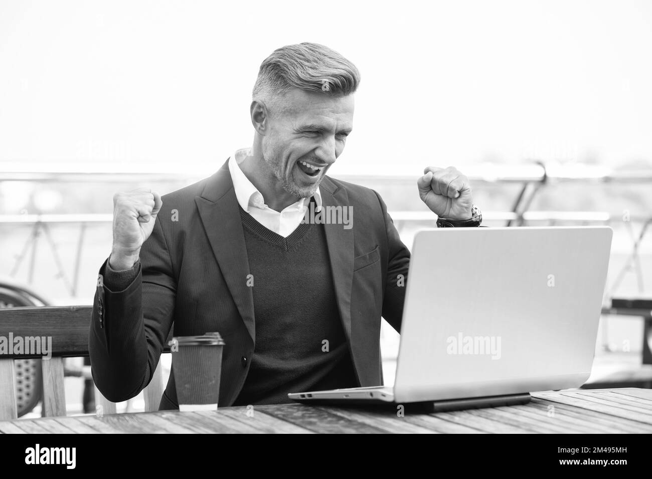 Happy professional man employee make winning gesture working on laptop ...