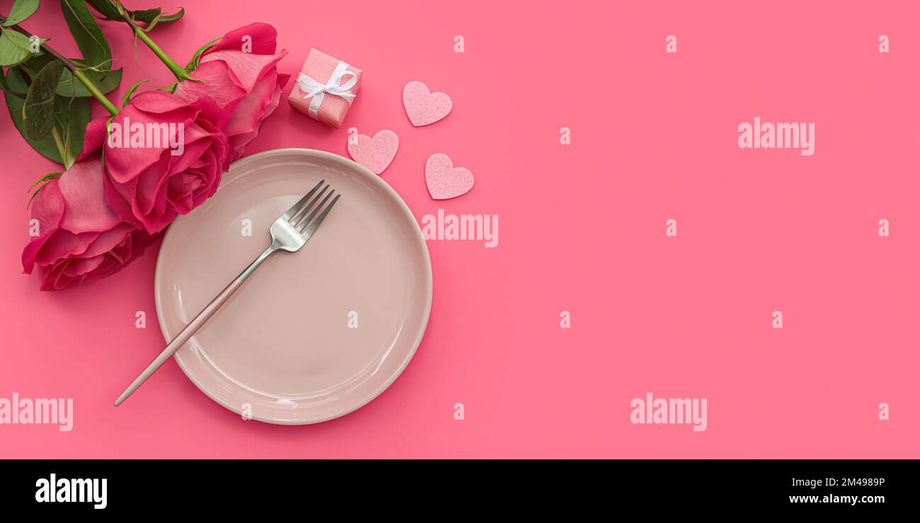 Table setting for Valentine's Day with roses and gift on pink ...