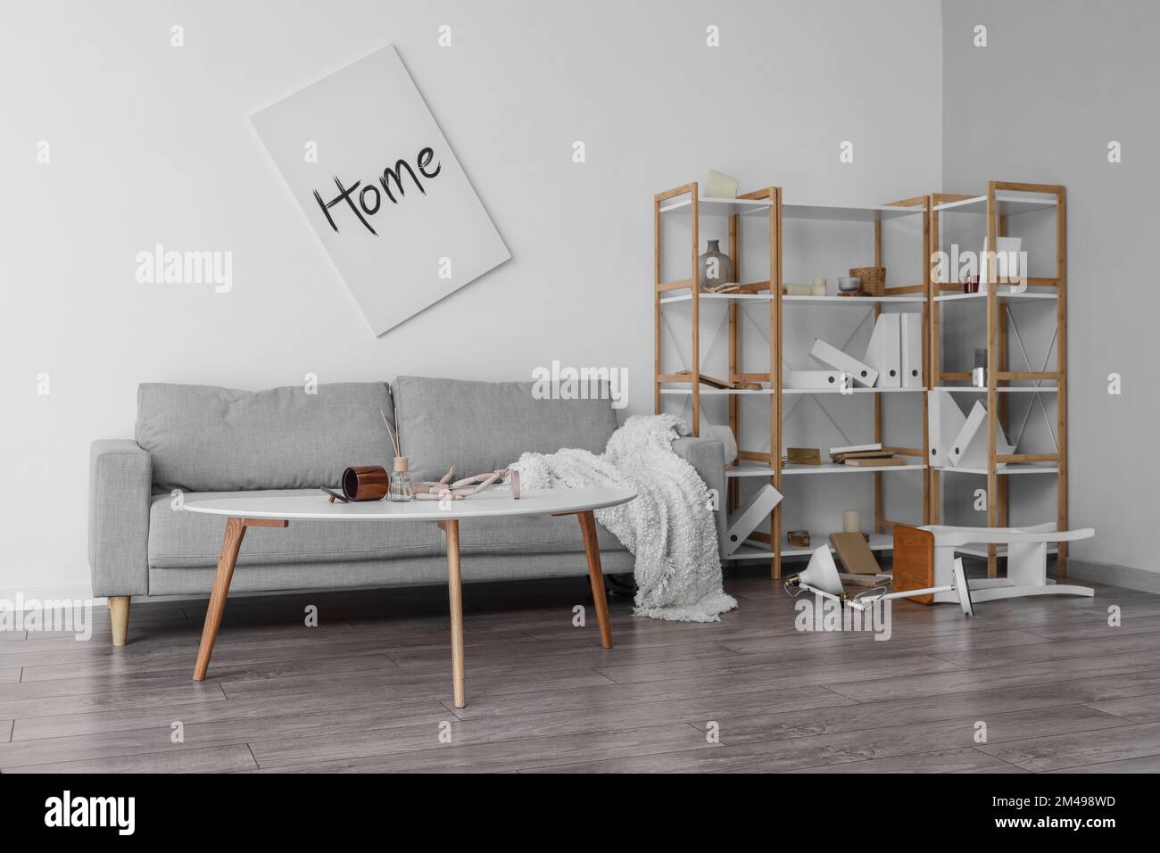 Interior of messy living room with grey sofa, tables and shelving unit ...