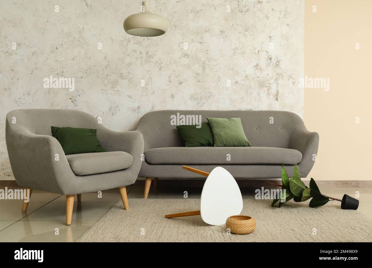 Interior of living room with armchair, sofa and overturned table near ...