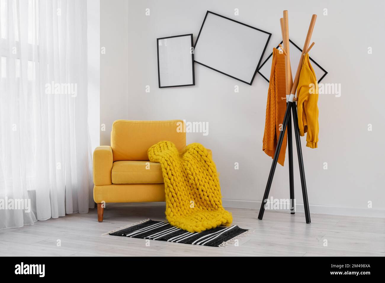 Interior of messy living room with yellow armchair, clothes stand and ...
