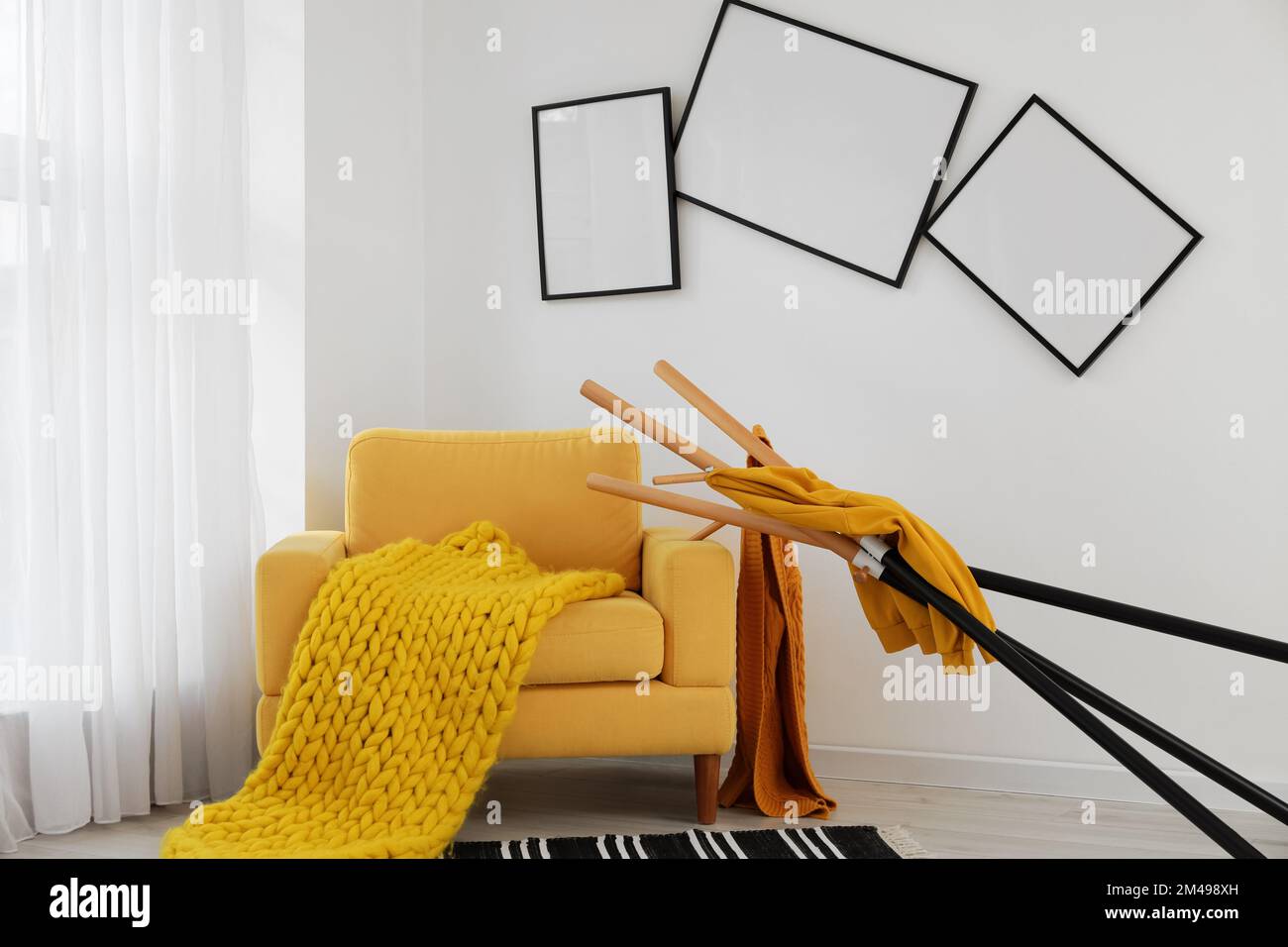 Interior of messy living room with yellow armchair, clothes stand and ...