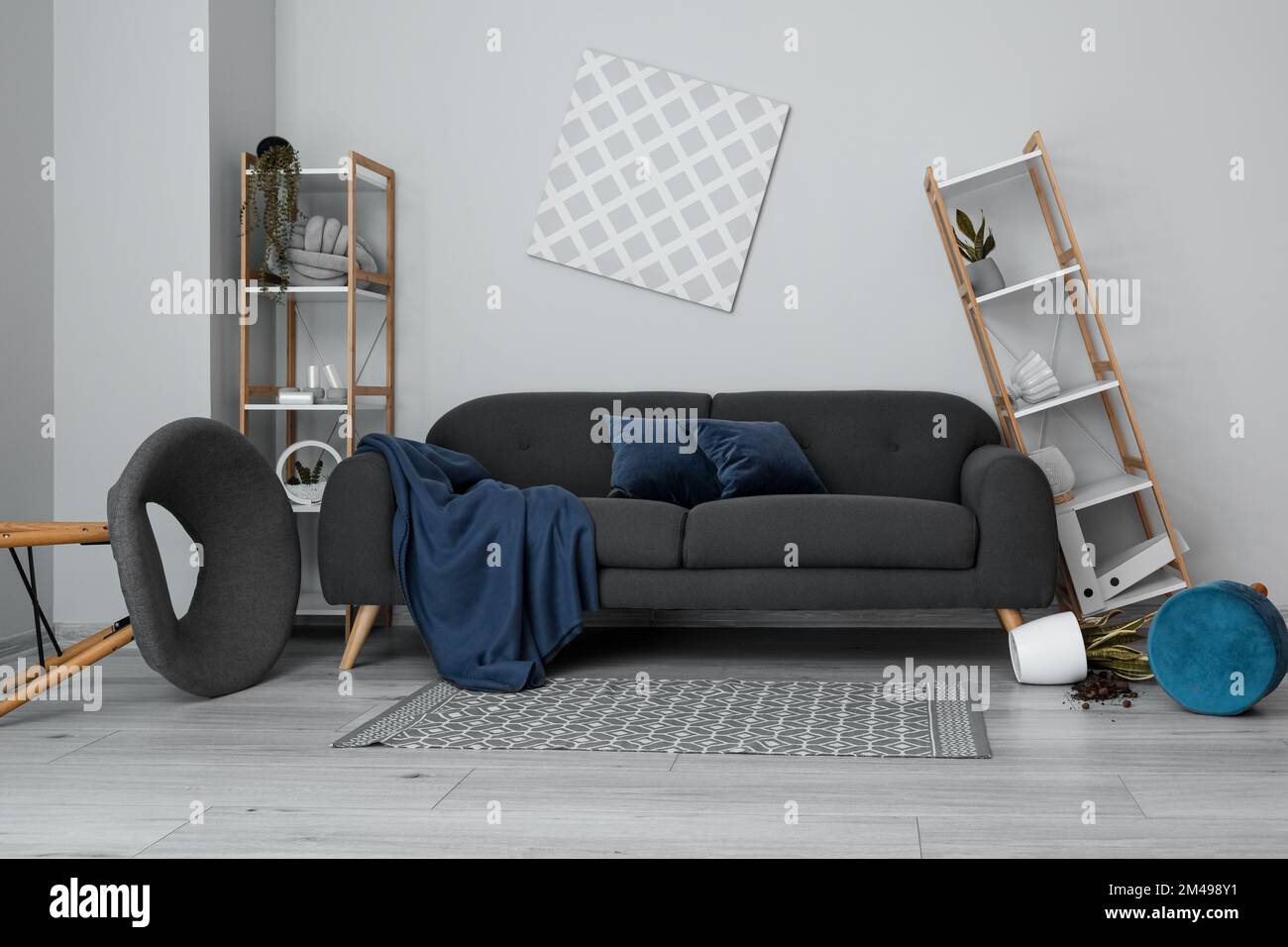 Interior of messy living room with shelf units and sofa near light wall ...