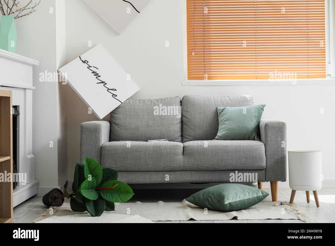 Messy interior of living room with sofa near white wall Stock Photo - Alamy