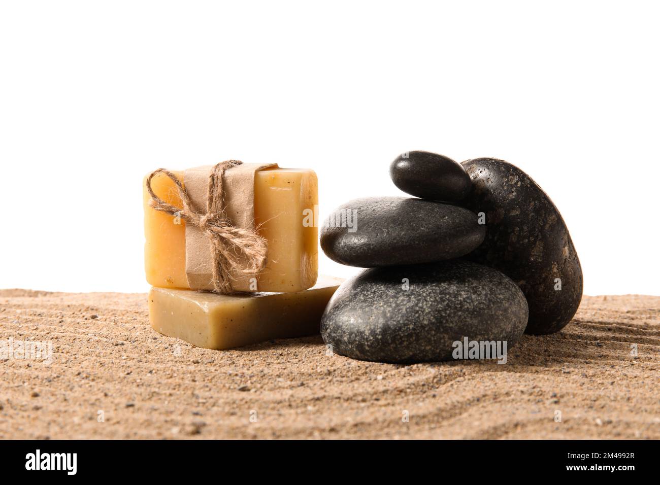 Soap bars with spa stones on sand against white background Stock Photo ...