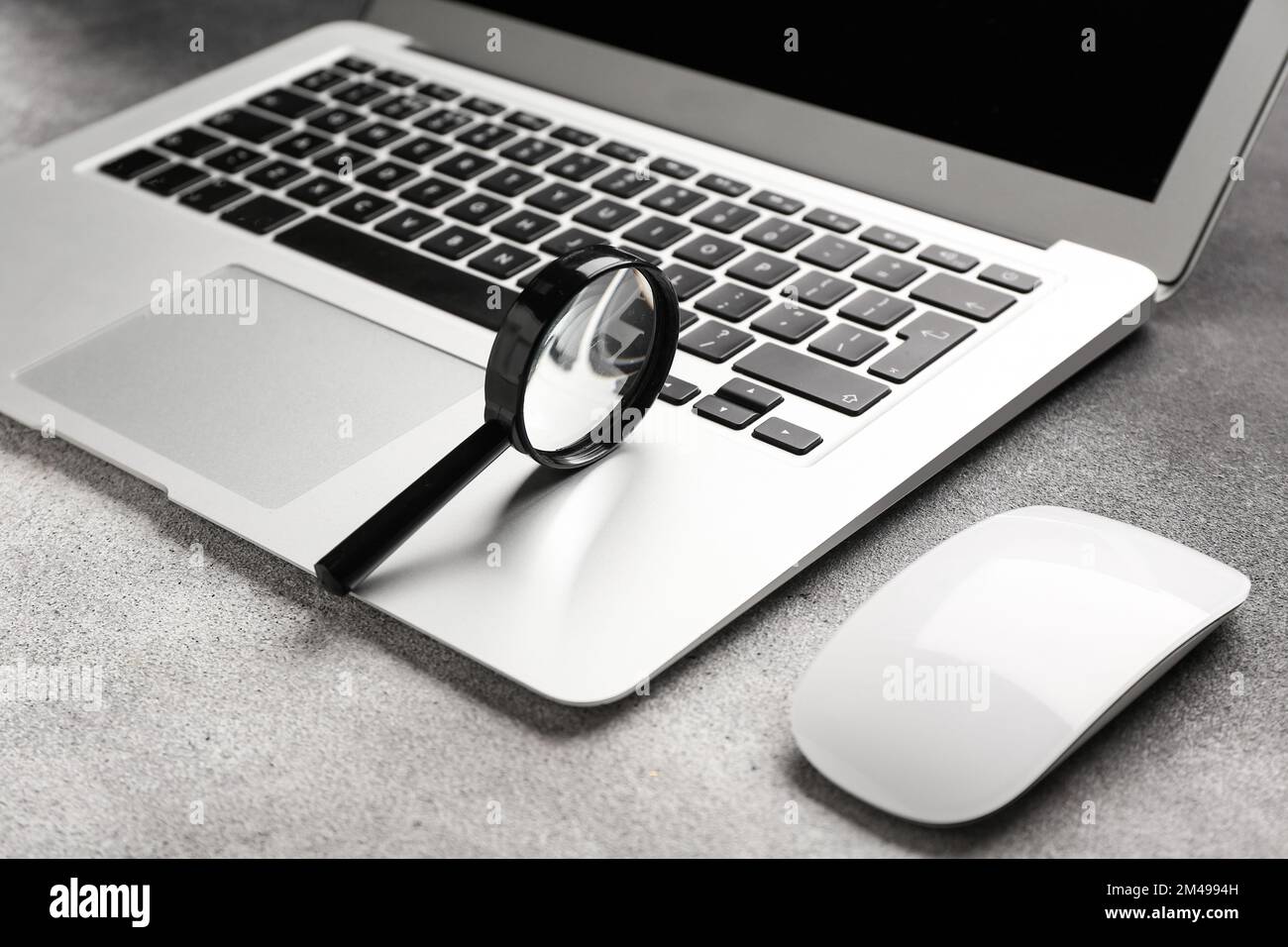 Laptop, computer mouse and magnifying glass on table. Internet search ...