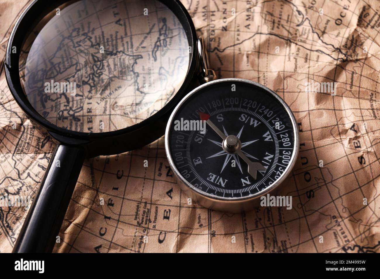 Compass and magnifier on world map Stock Photo - Alamy