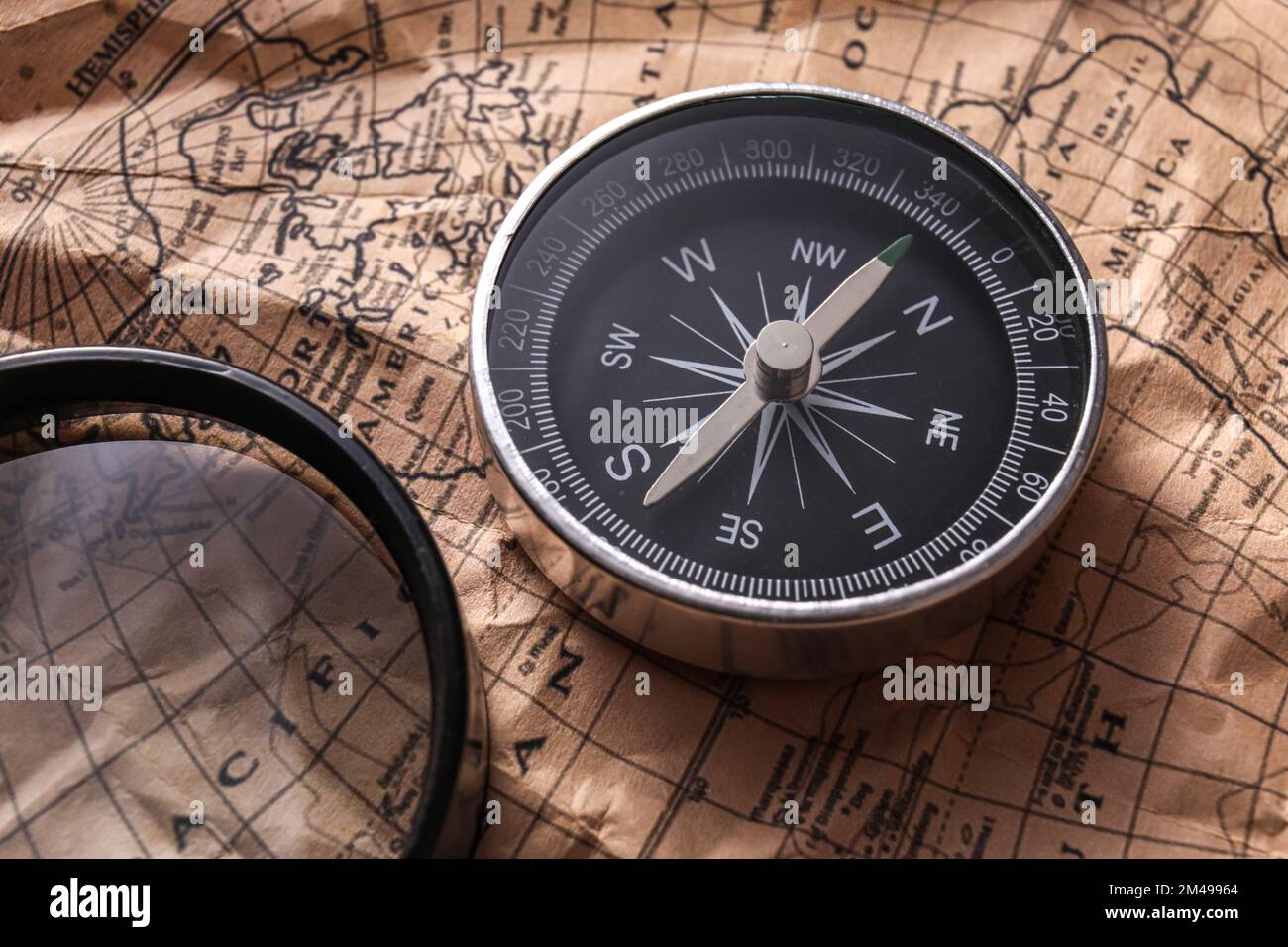 Compass and magnifier on world map, closeup Stock Photo - Alamy