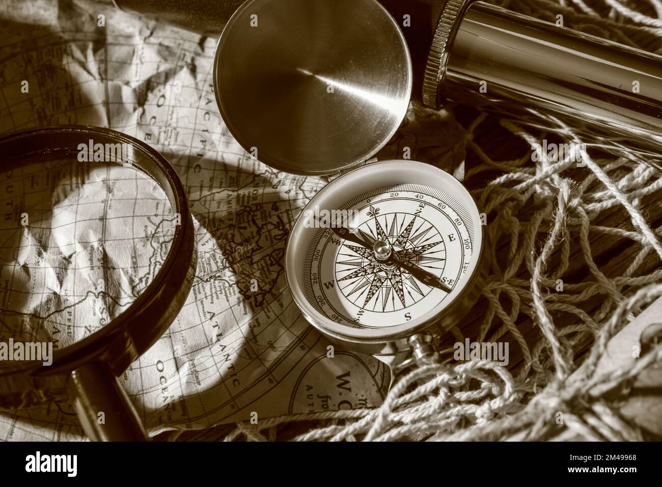 Compass with magnifier, map, spyglass and net on wooden background ...