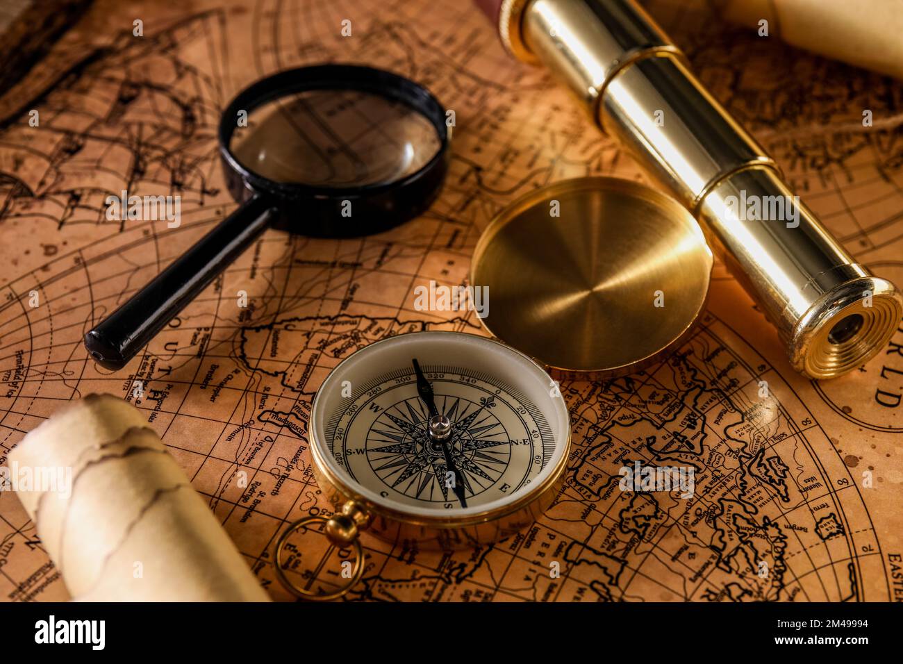Golden compass, magnifier and spyglass on world map Stock Photo - Alamy