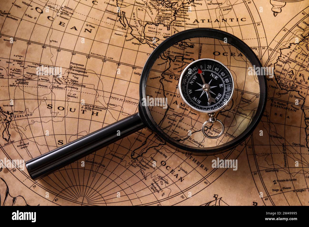 Compass and magnifier on world map Stock Photo - Alamy
