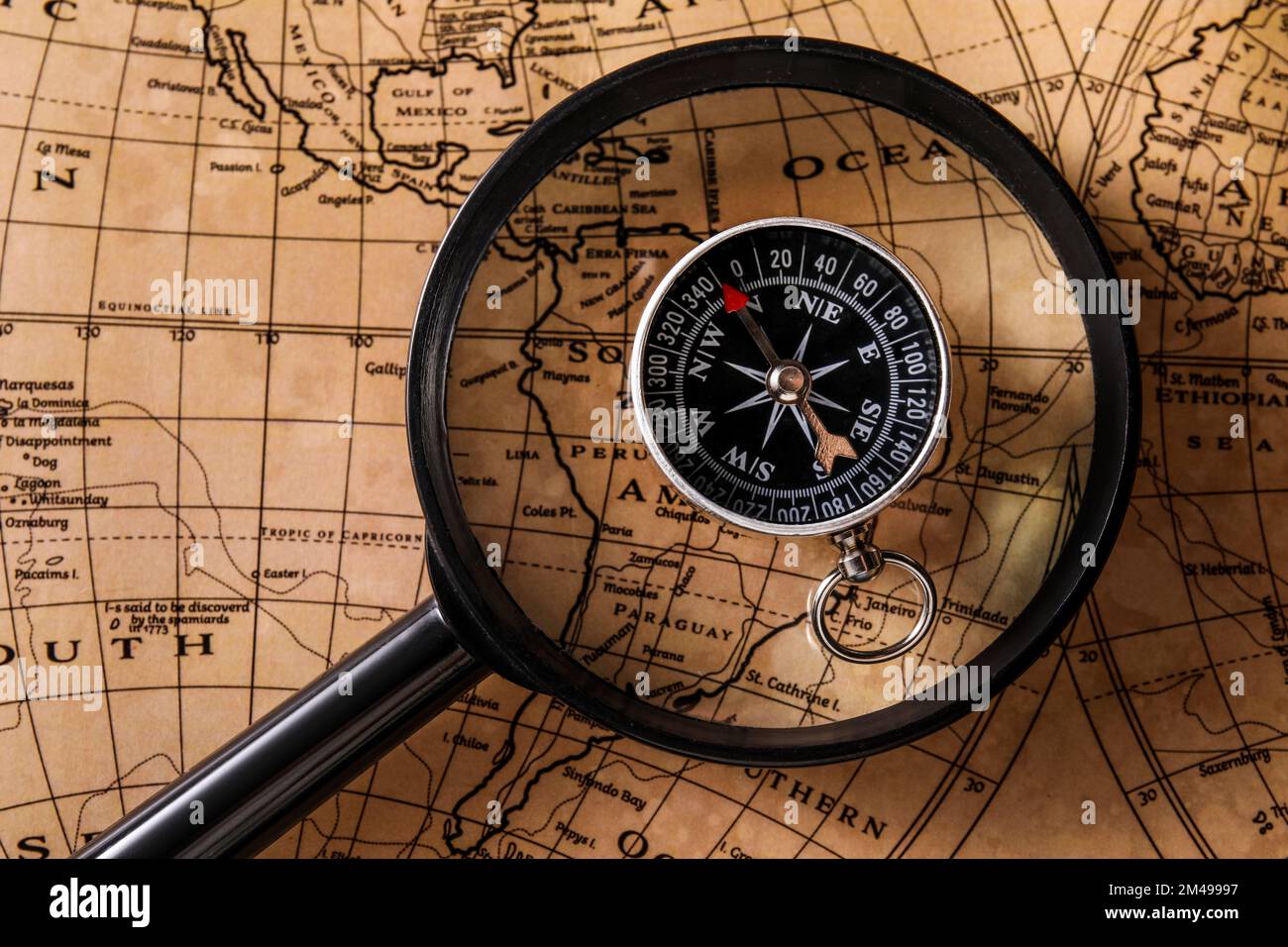 Compass and magnifier on world map Stock Photo - Alamy