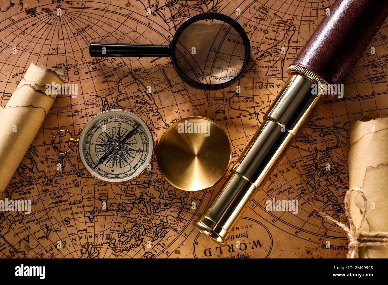 Golden compass, magnifier and spyglass on world map Stock Photo - Alamy