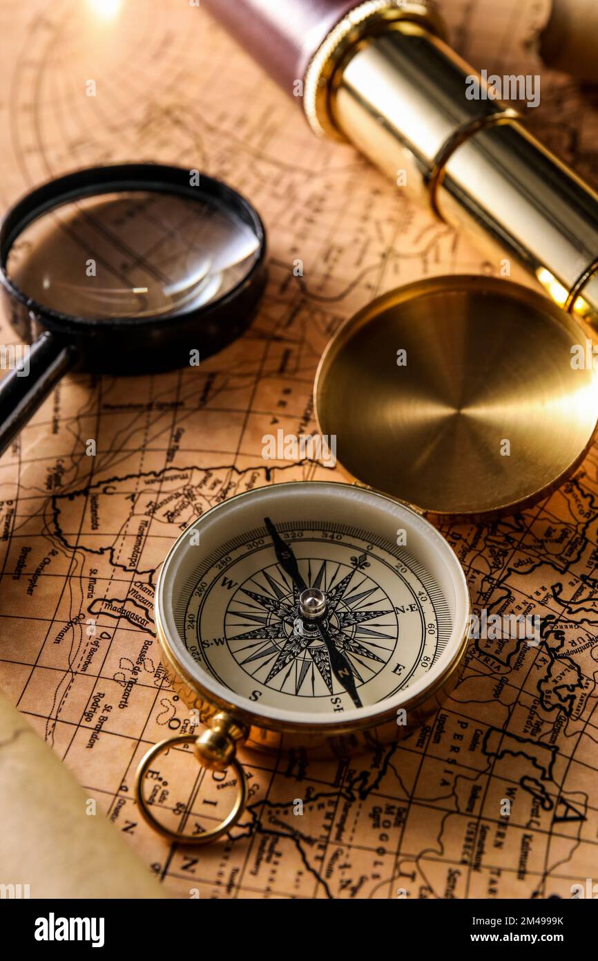 Golden compass, magnifier and spyglass on world map Stock Photo - Alamy