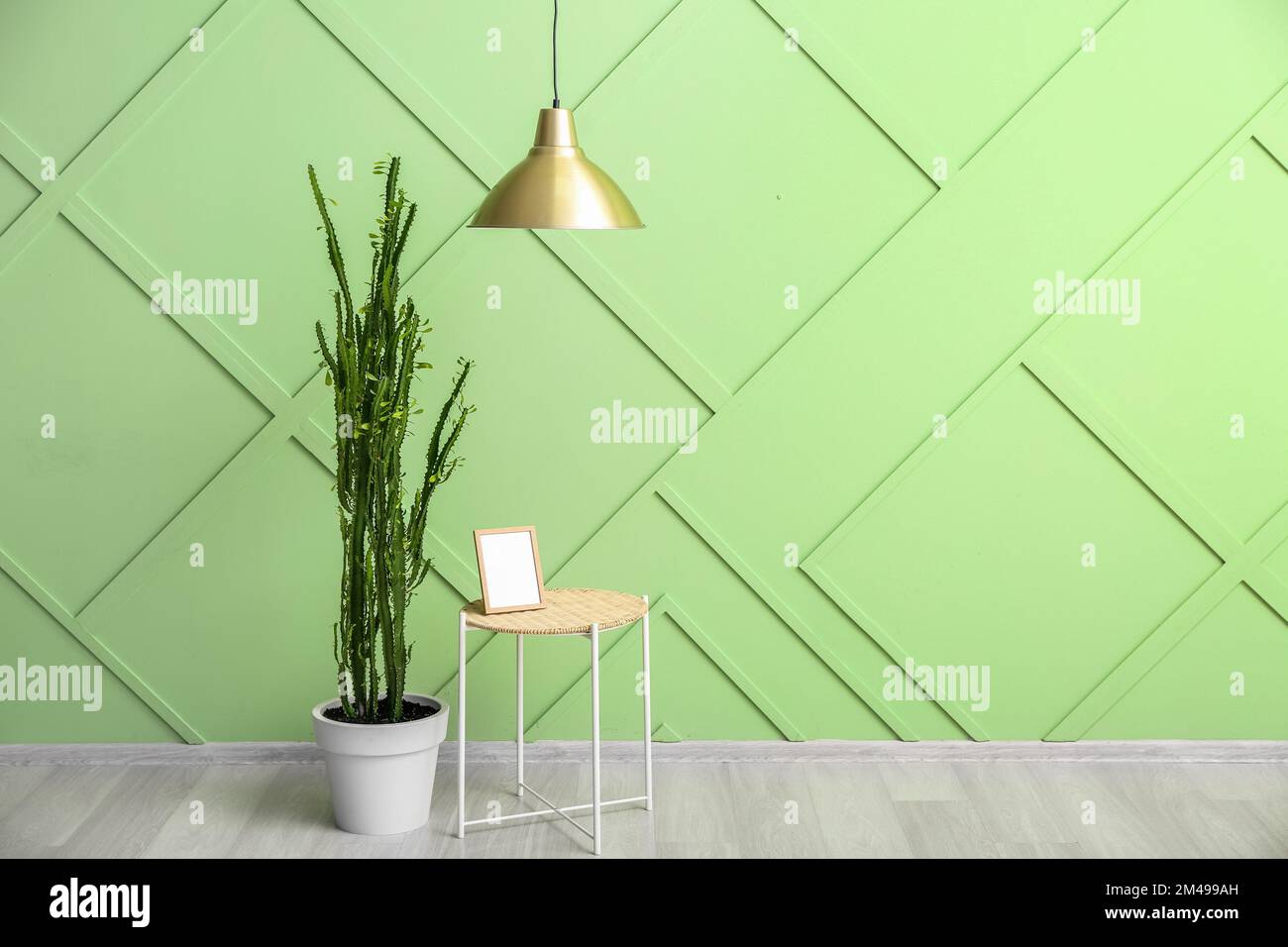 Table with blank photo frame and cactus near green wall in room Stock ...