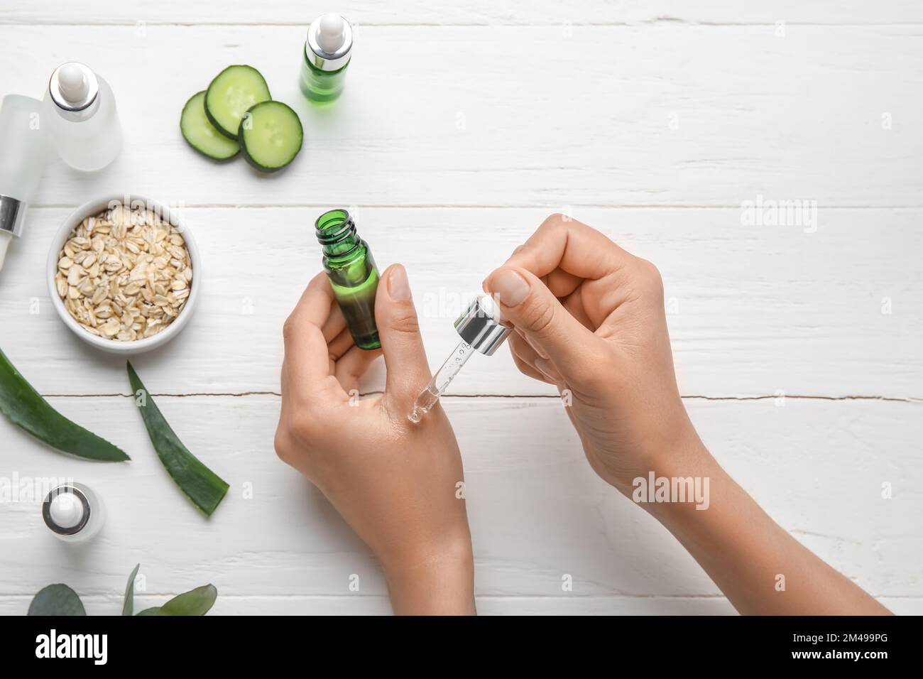 Woman applying essential oil on light wooden background Stock Photo - Alamy