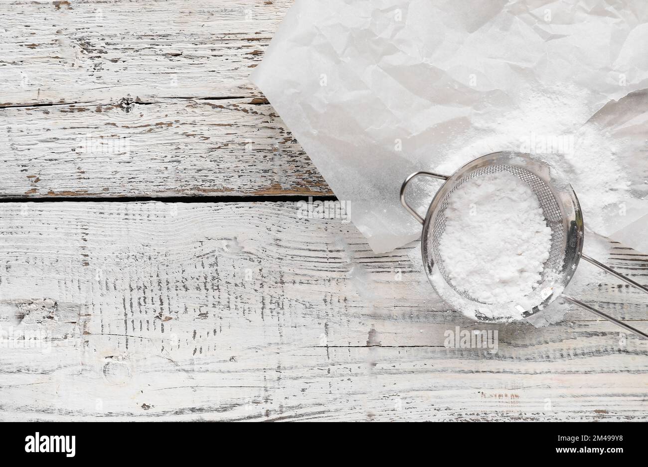 Baking paper and sieve with flour on white wooden background Stock ...