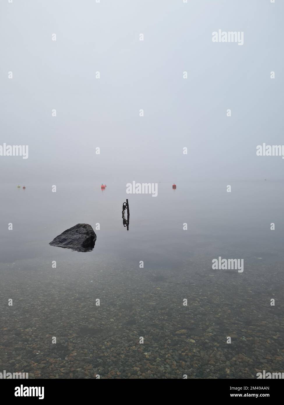 A vertical of sea with stones under the surface on a dense misty day ...