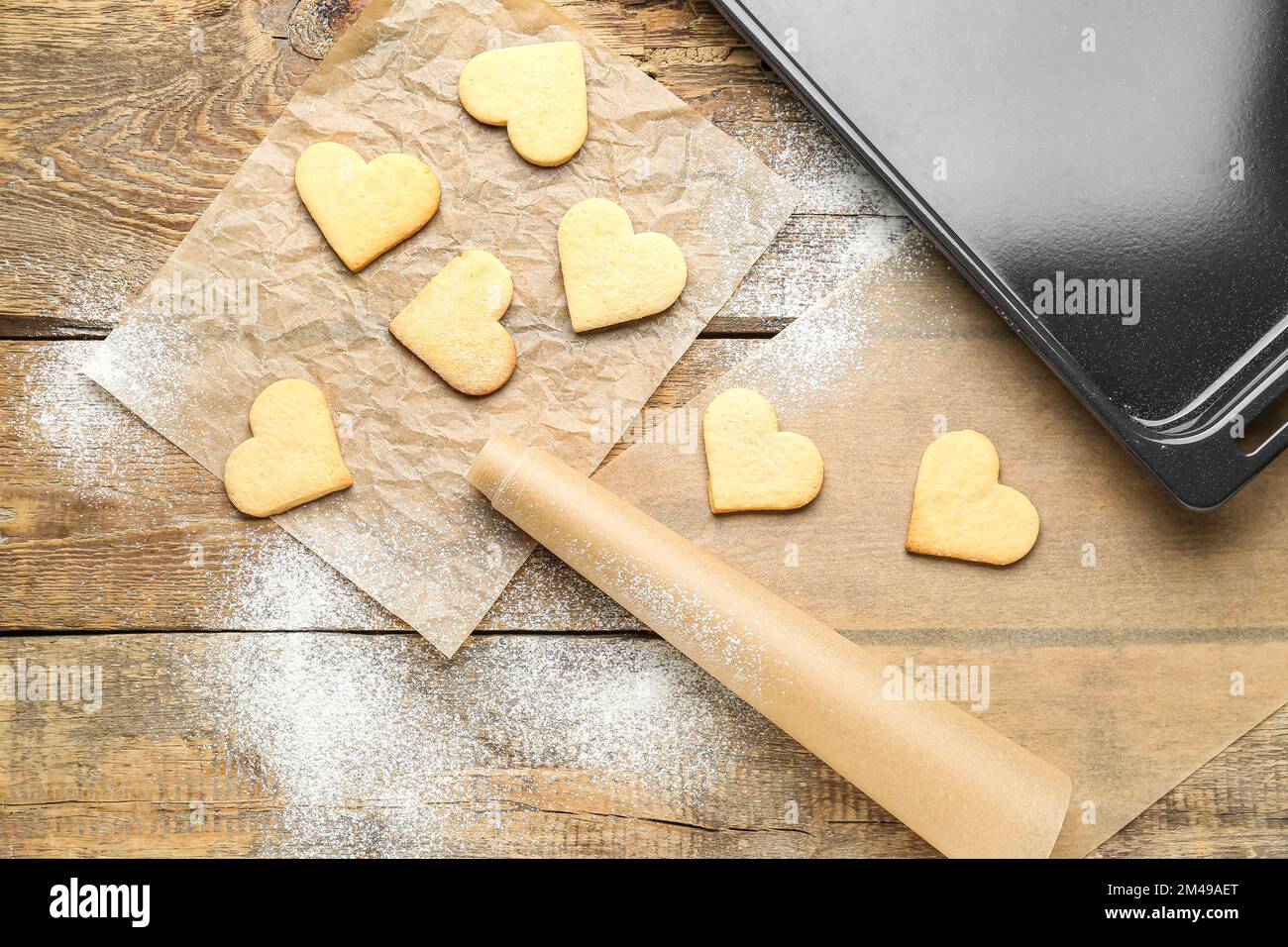 Heart shaped cookies on baking paper against wooden background Stock ...