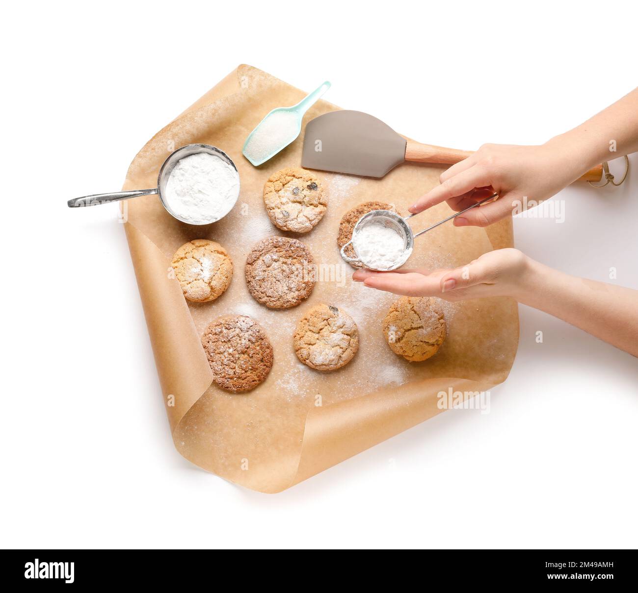 Woman sprinkling sugar powder onto tasty cookies on white background ...