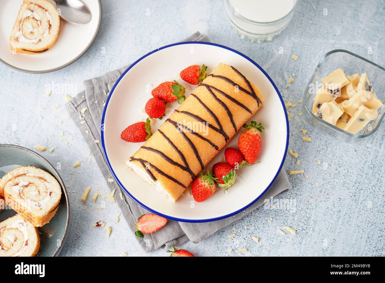 Plate with delicious sponge cake roll, fresh strawberries and glass of ...