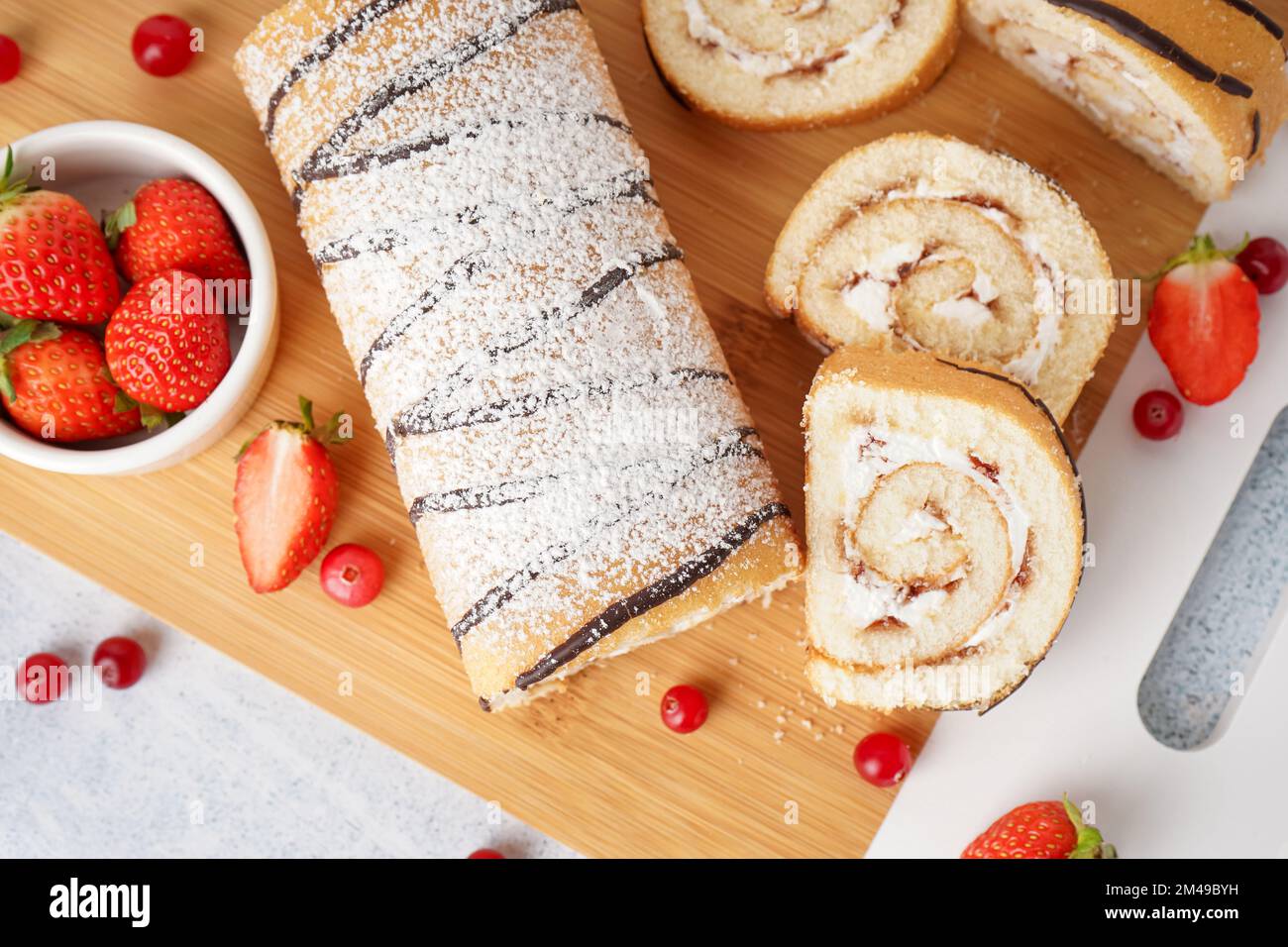Cutting board with delicious sponge cake roll and fresh berries on ...