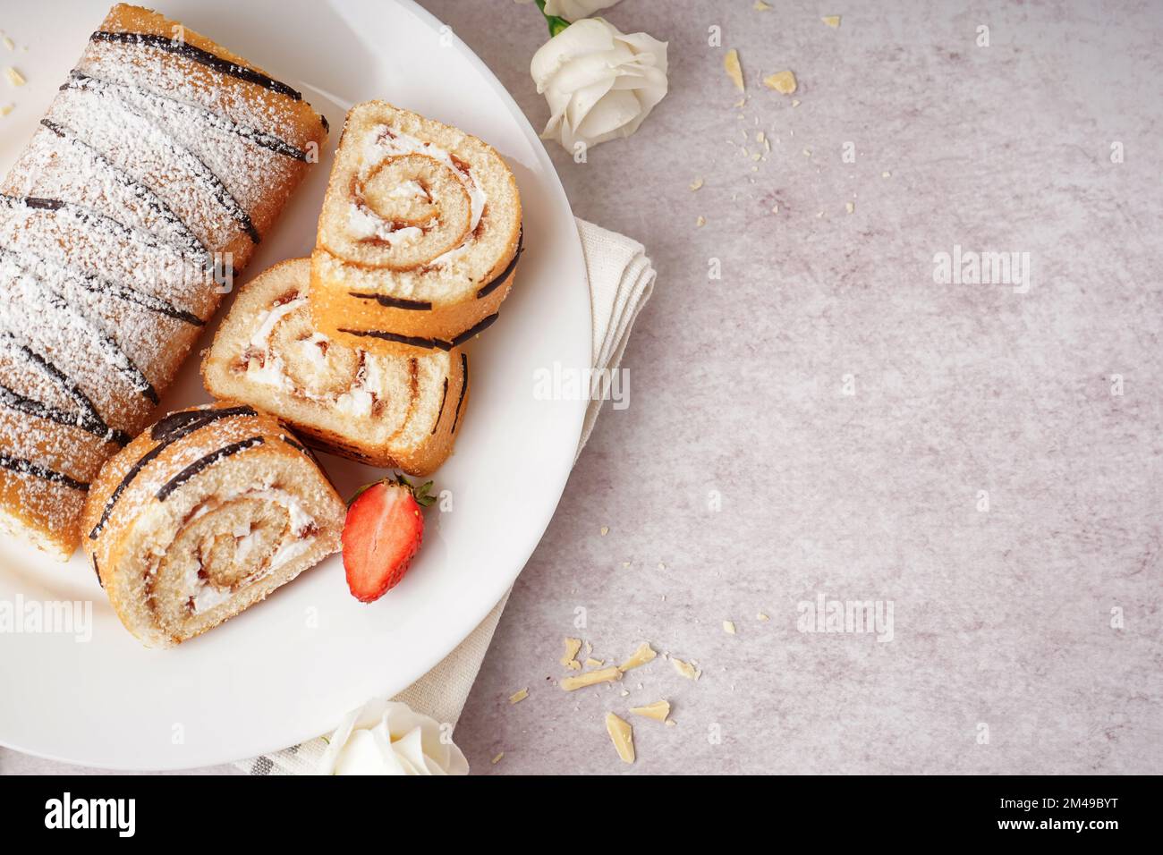 Plate with delicious sponge cake roll, fresh strawberries and floral ...