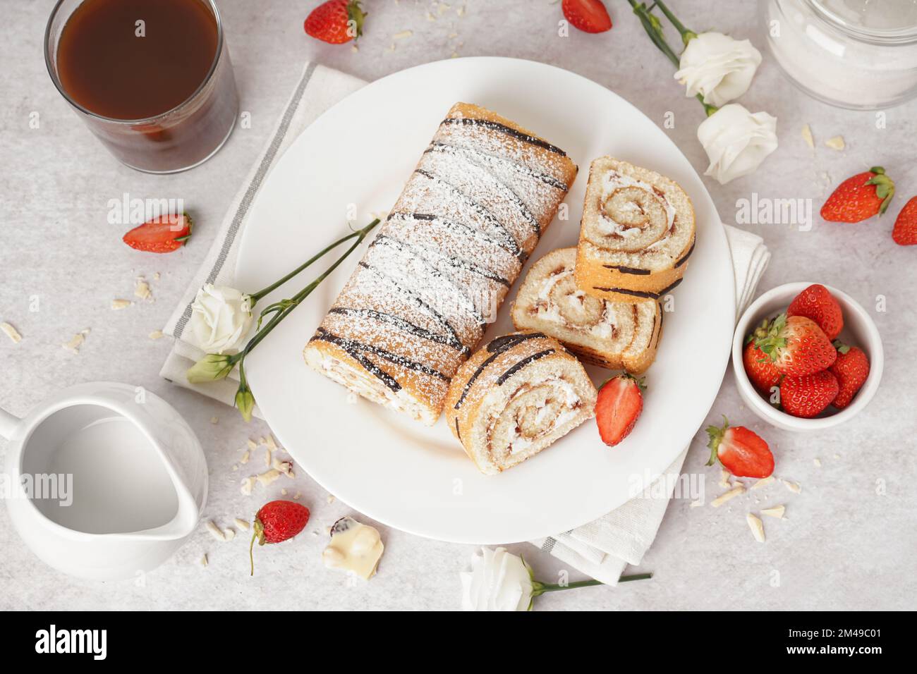Plate with delicious sponge cake roll, fresh strawberries, floral decor ...