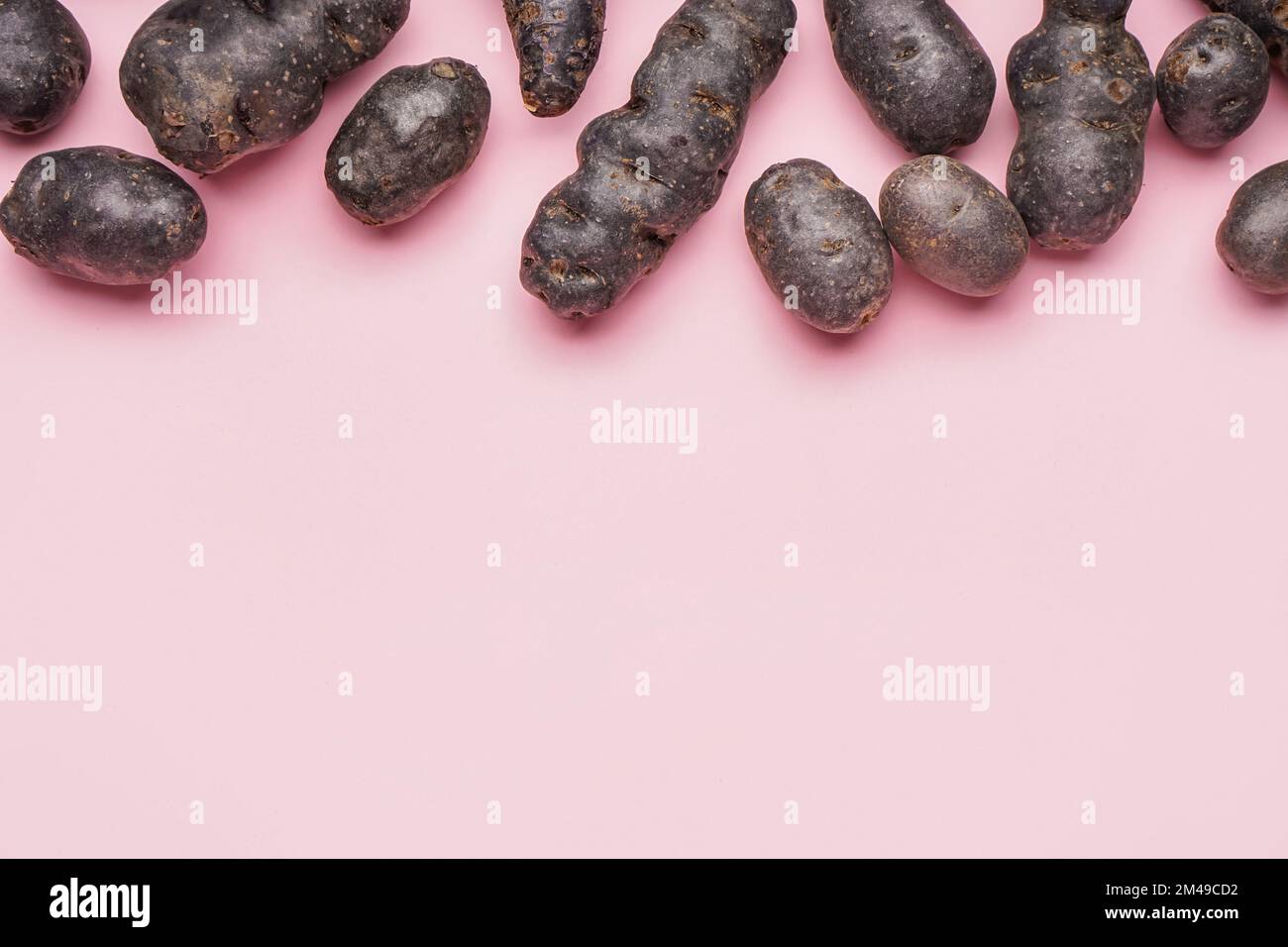 Raw purple potatoes on pink background Stock Photo - Alamy