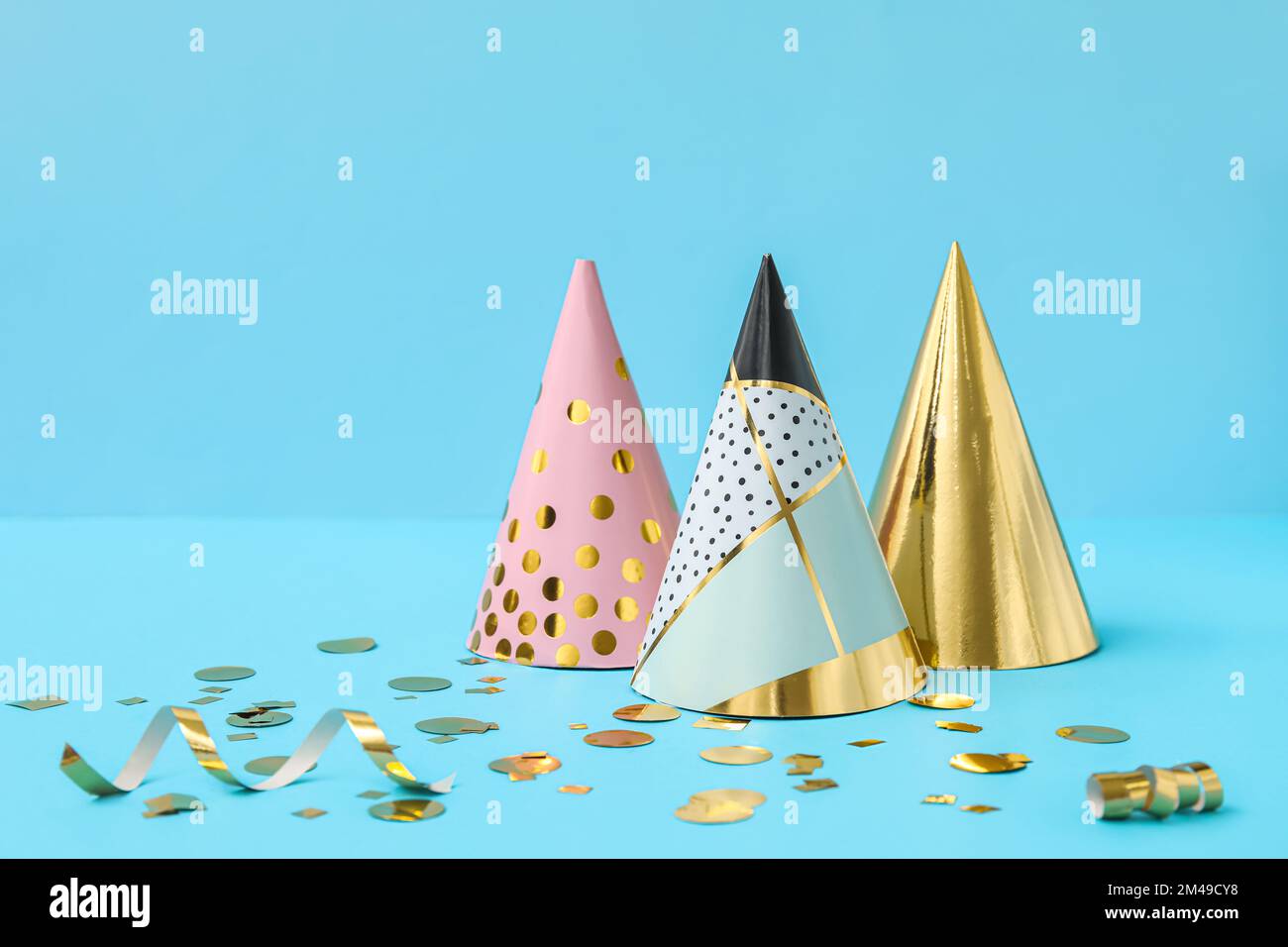 Party hats and confetti on blue background Stock Photo - Alamy
