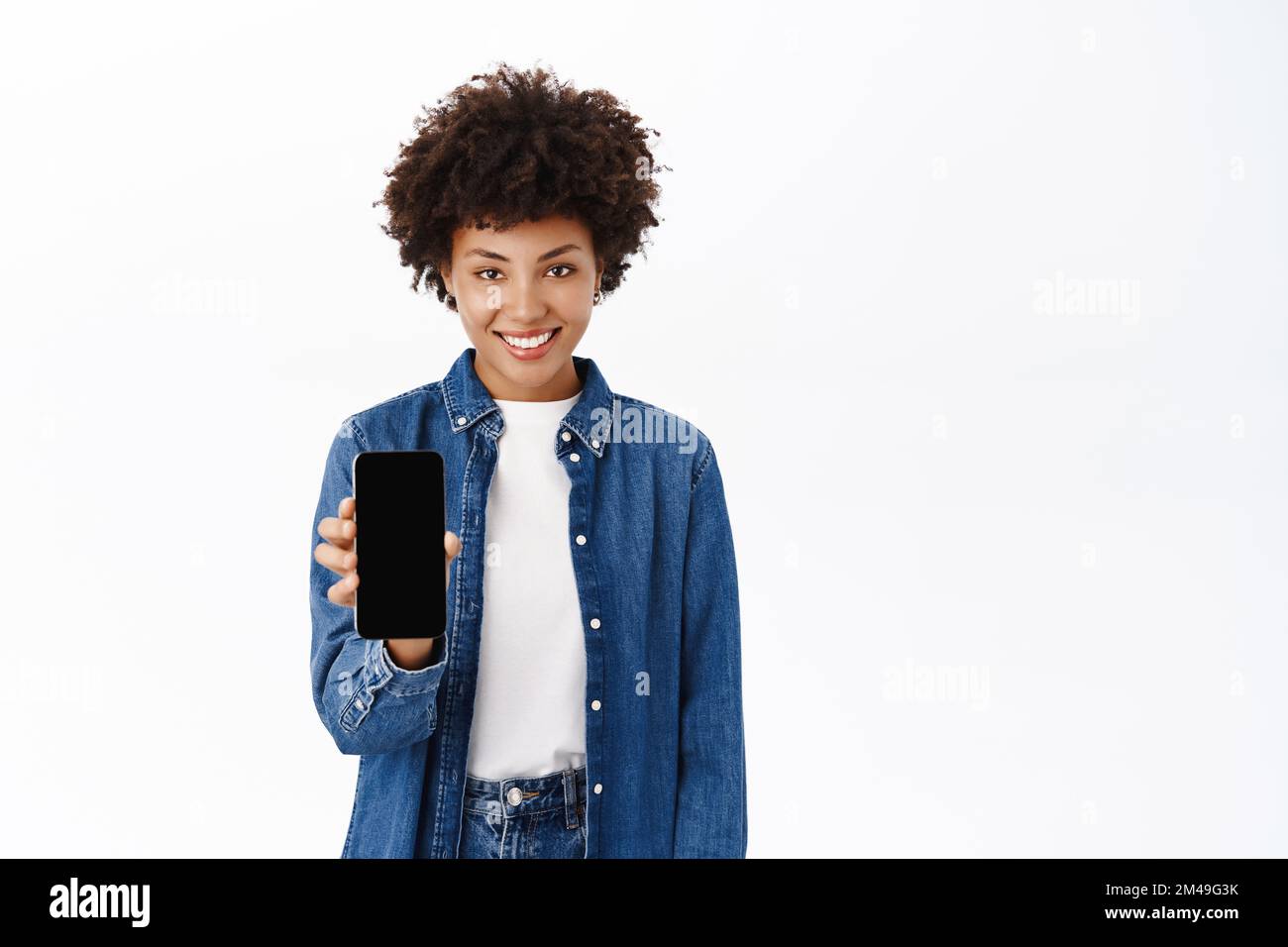 Smiling young modern girl shows mobile phone screen, demonstrates ...