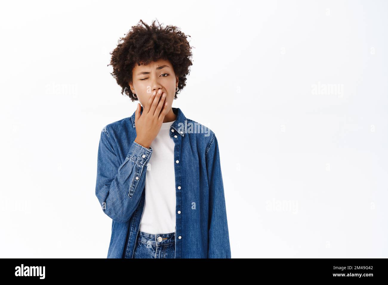 Tired young woman yawns, looks tired or sleepy, bored of smth, stands ...