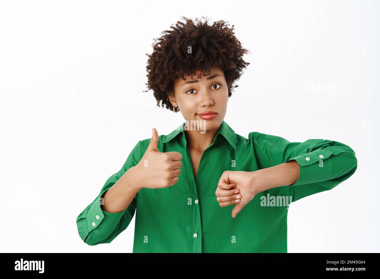 Young woman shows thumbs up and thumbs down with doubt, confused ...