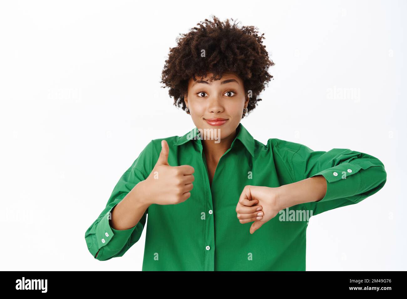 Young woman shows thumbs up and thumbs down with doubt, confused ...