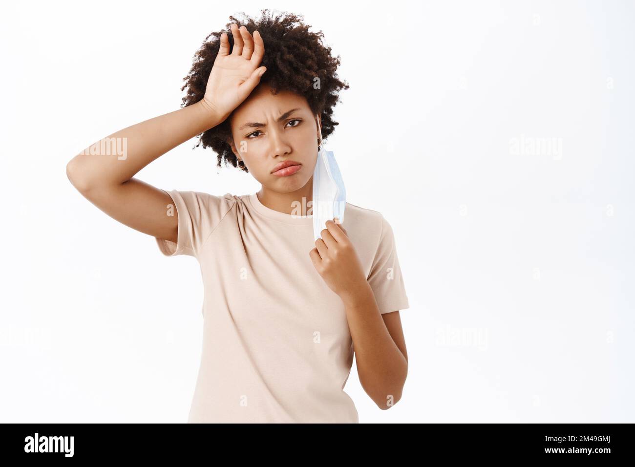 Young woman takes off medical face mask, feels hot and sweating ...