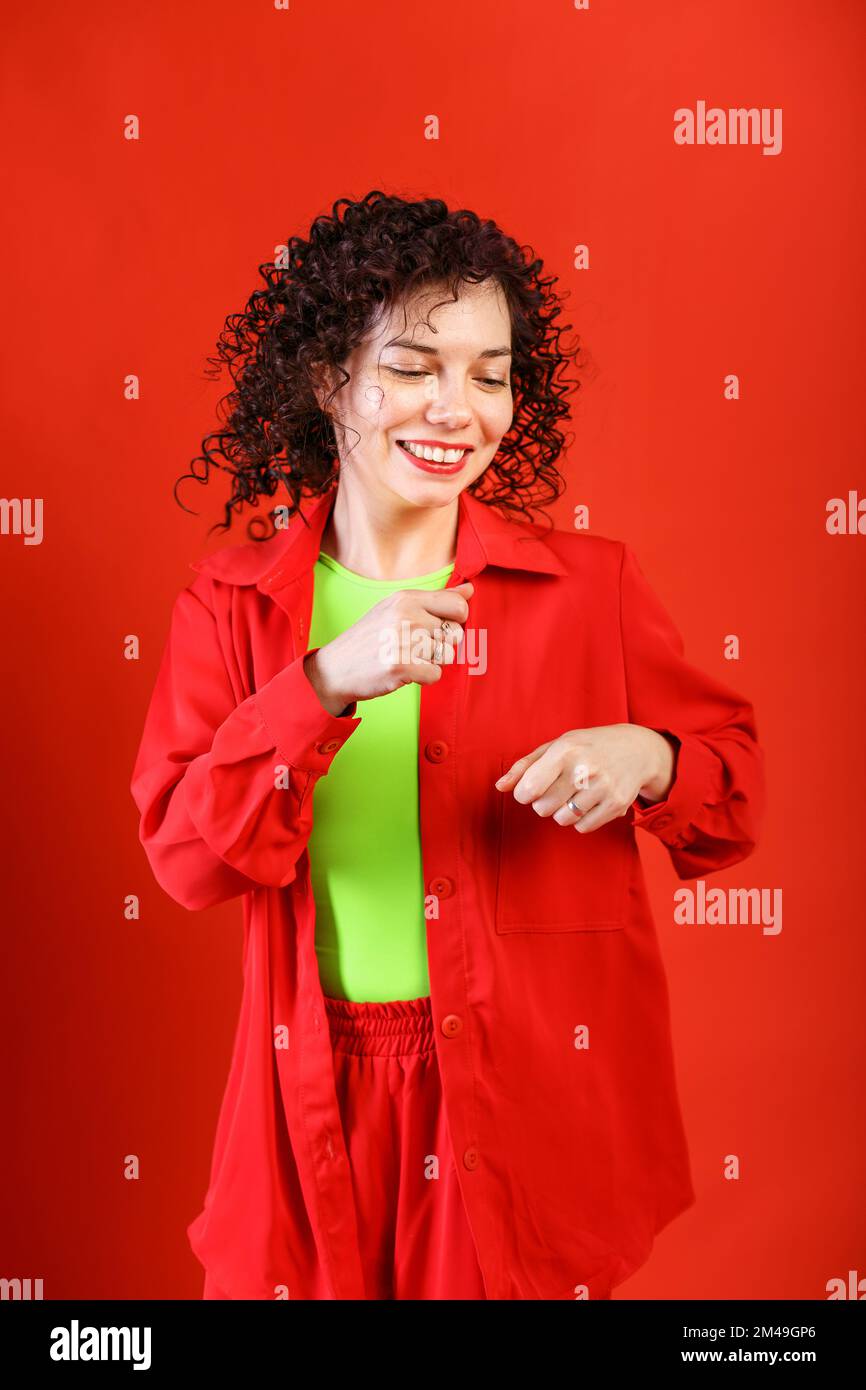Curly cute girl laughs and jumps. Studio portrait of a woman on a ...