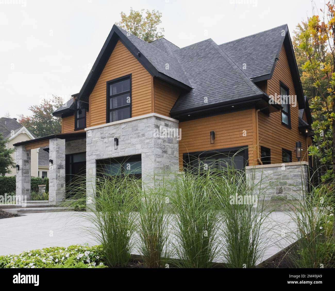 Gray cut stone and wood plank cladded cottage style upscale home with ...