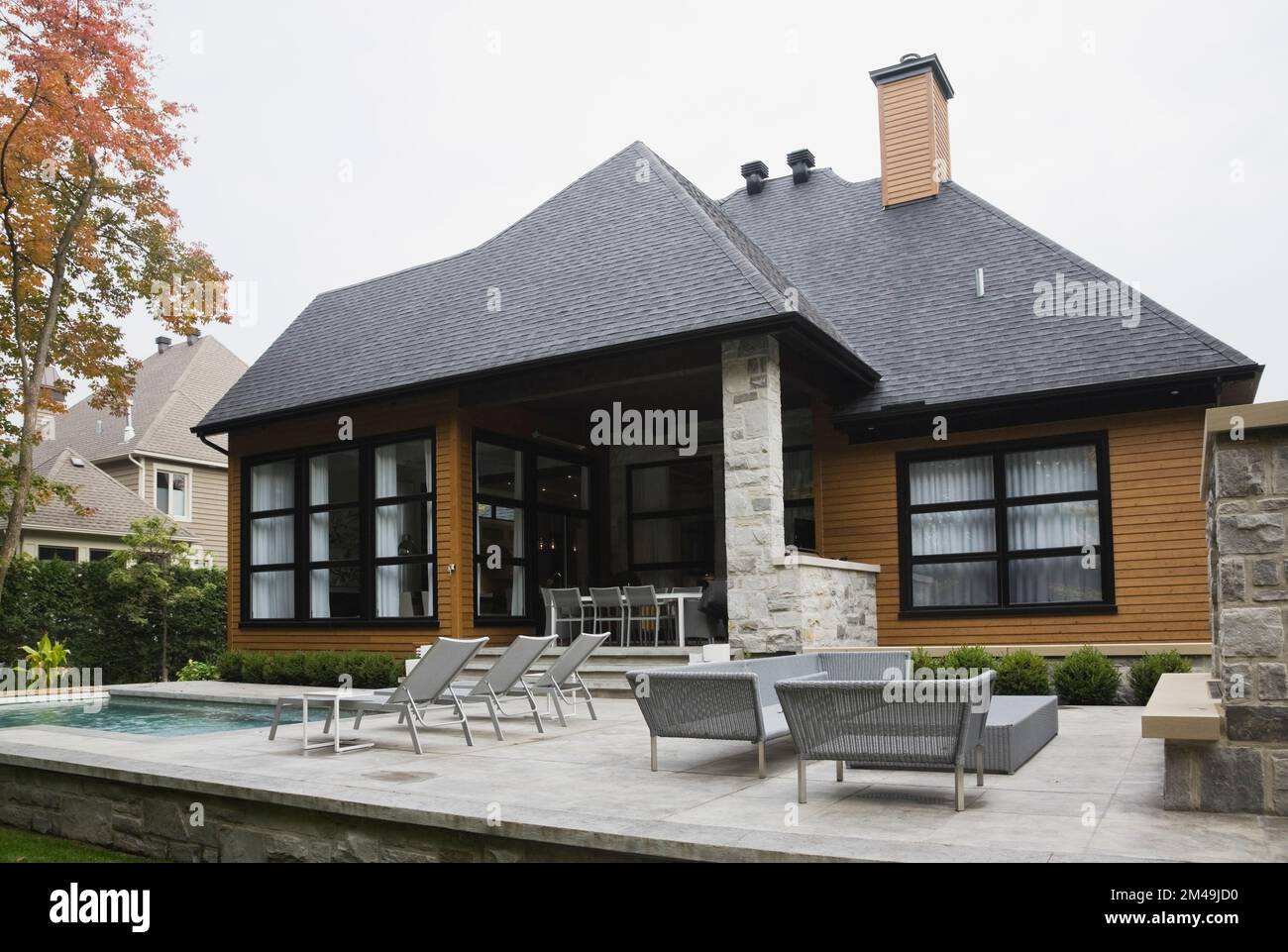 Rear view of gray cut stone and wood plank cladded cottage style home ...