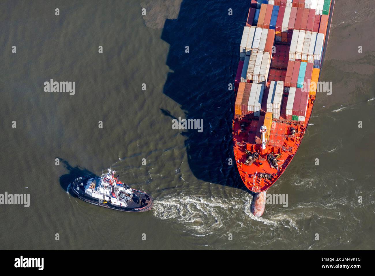 Aerial view of a tugboat pulling a container ship on the Elbe and ...