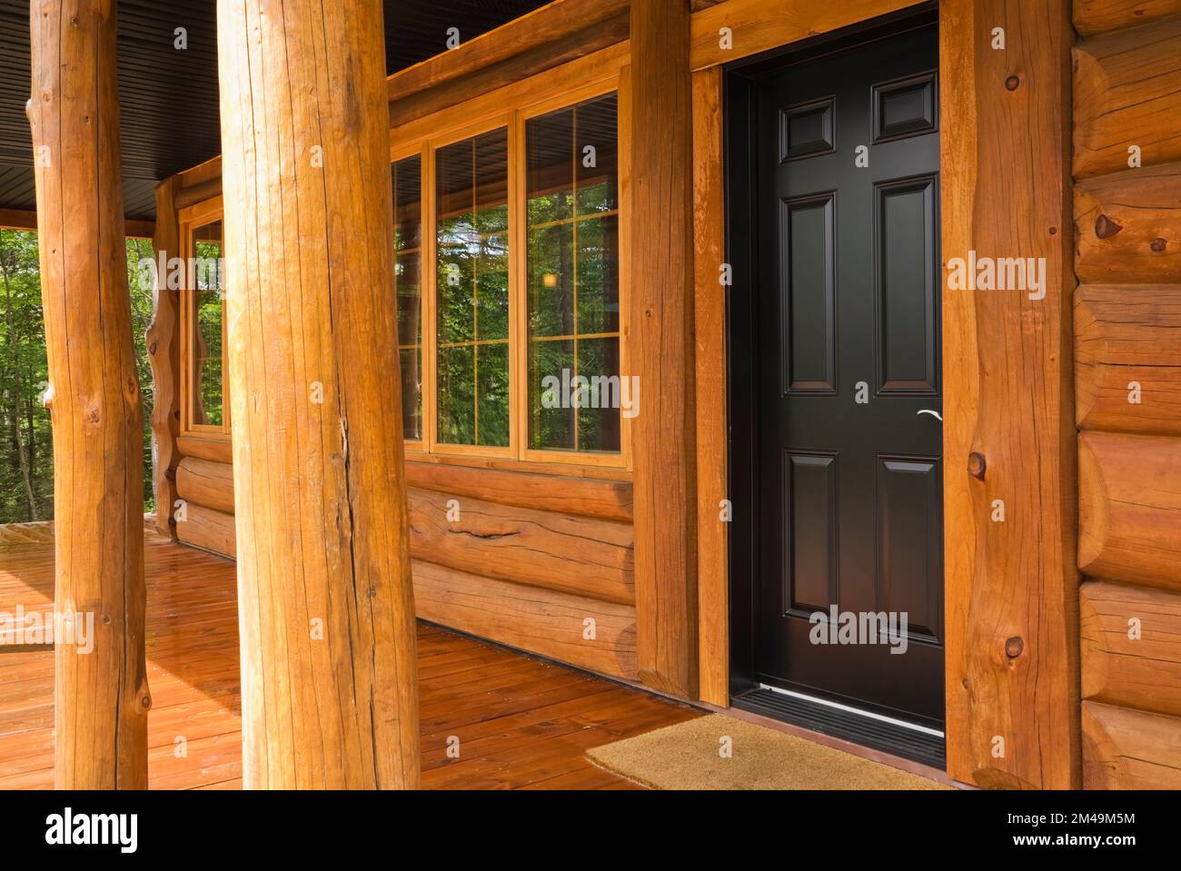 Rustic log home facade with panoramic glass pane windows and veranda ...