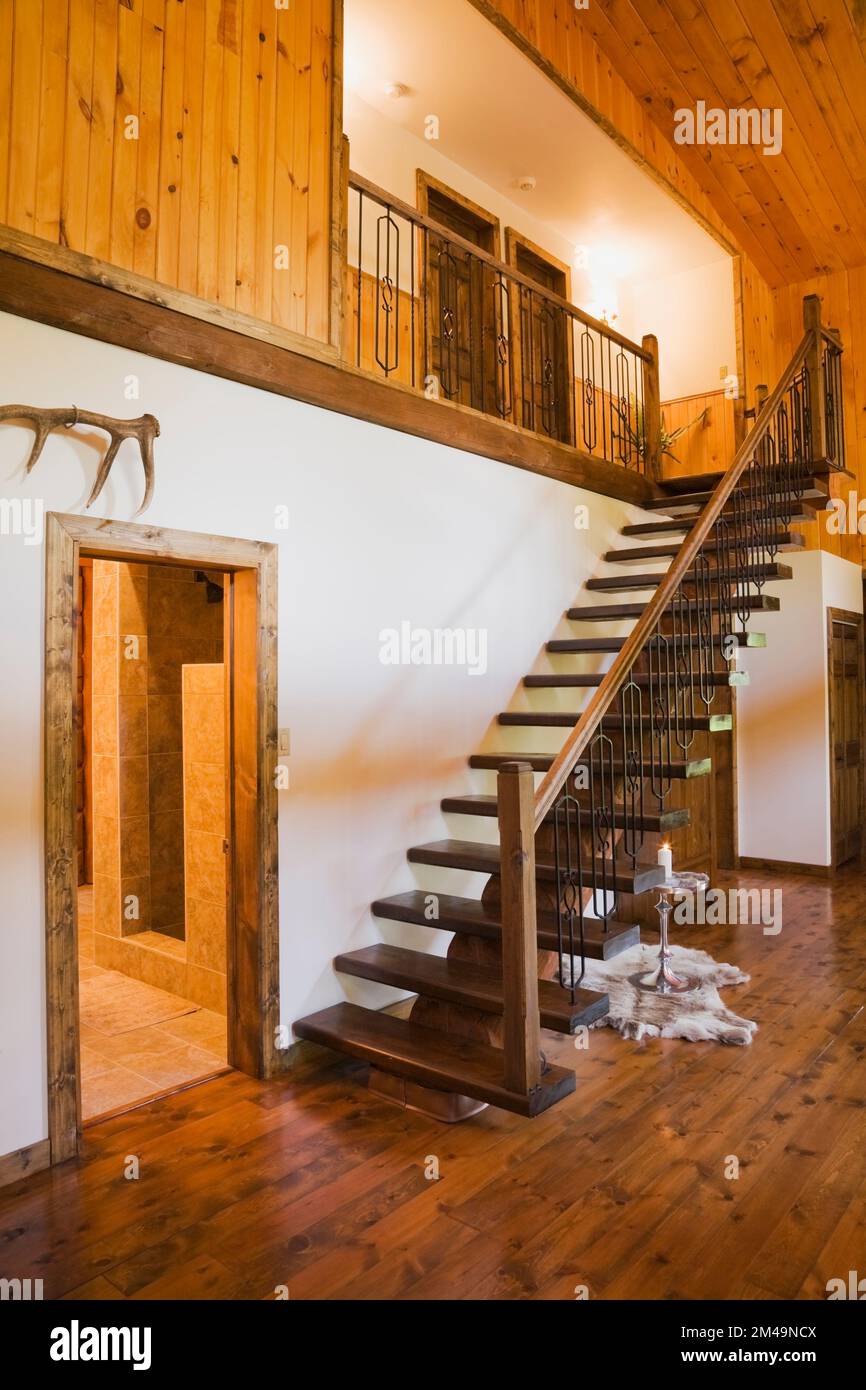 Wooden beam staircase leading to upstairs floor in hallway inside log ...